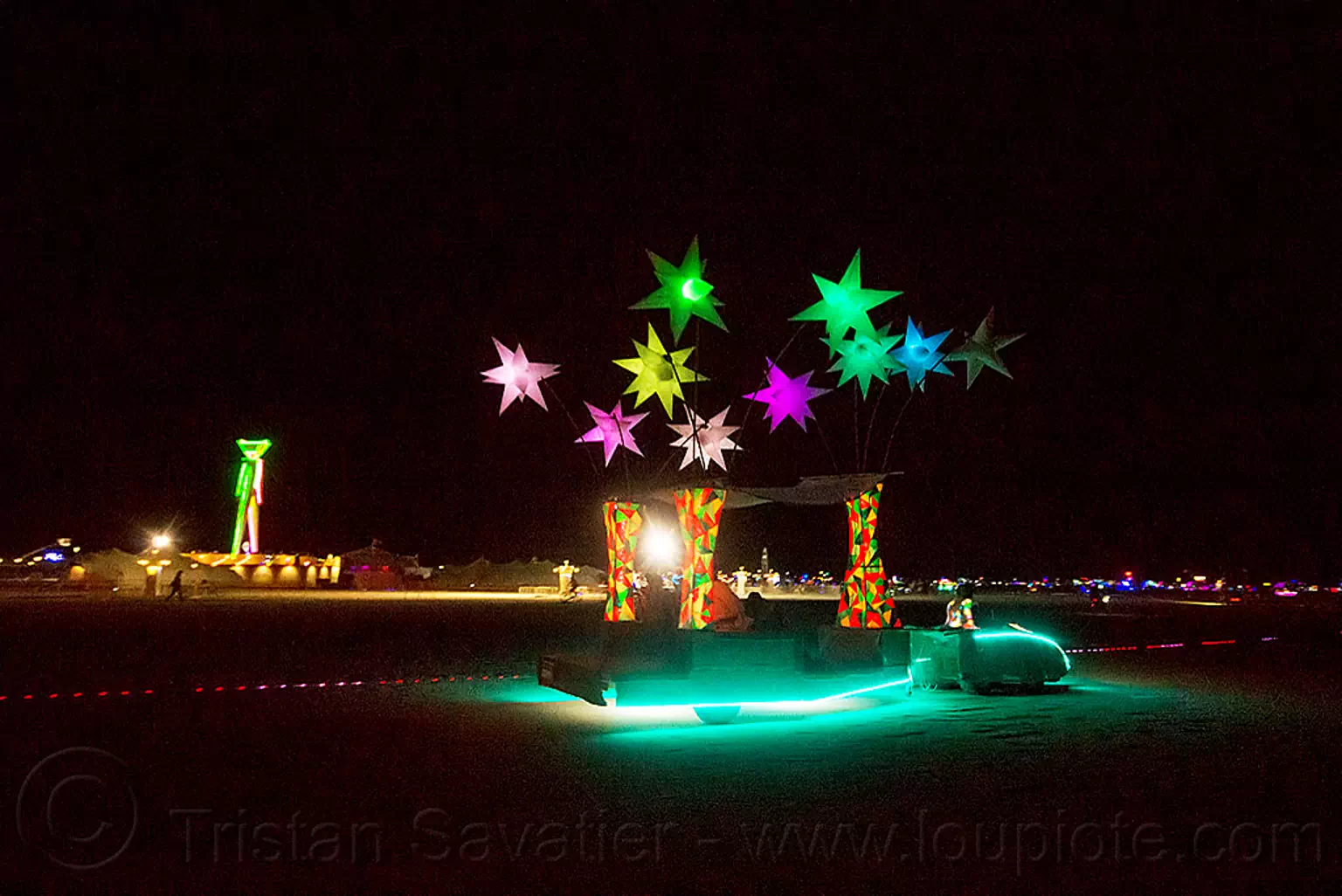 burning man, glowing art car with color stars, cool wind