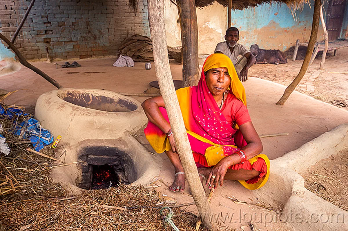 hindu woman sitting near mud stove