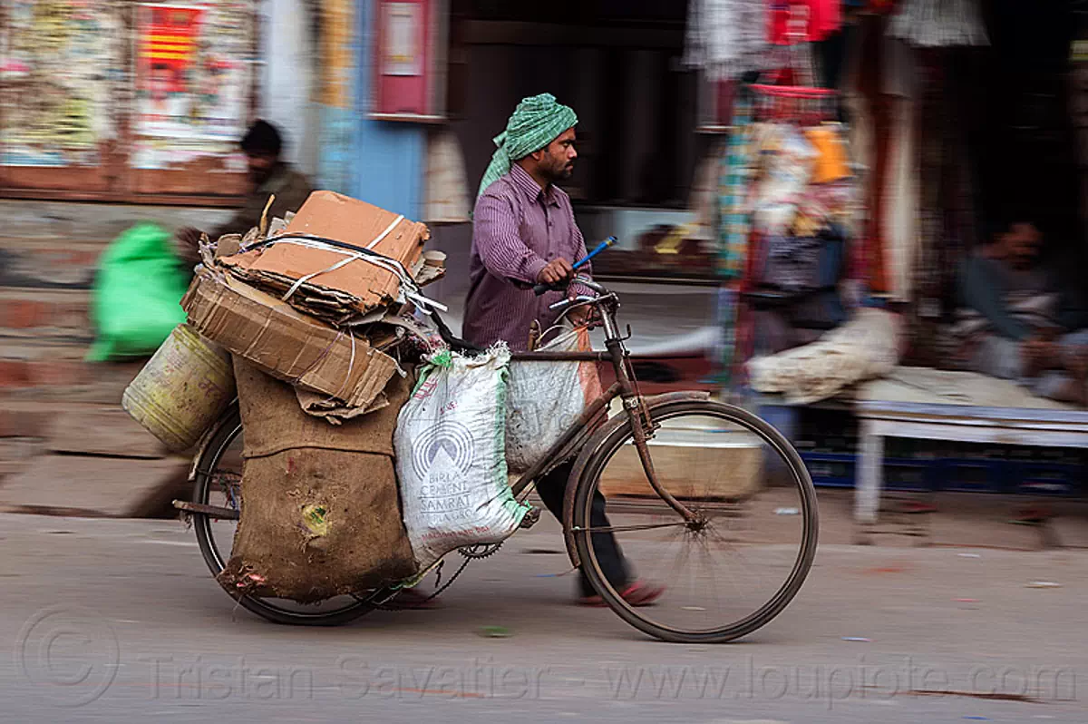 man pushing heavily loaded bicycle, india