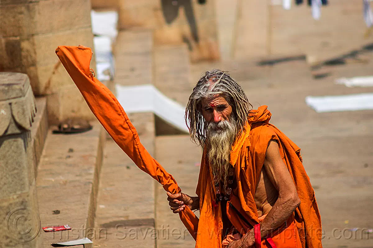 old hindu man in saffron color cloth on the ghats of varanasi, india