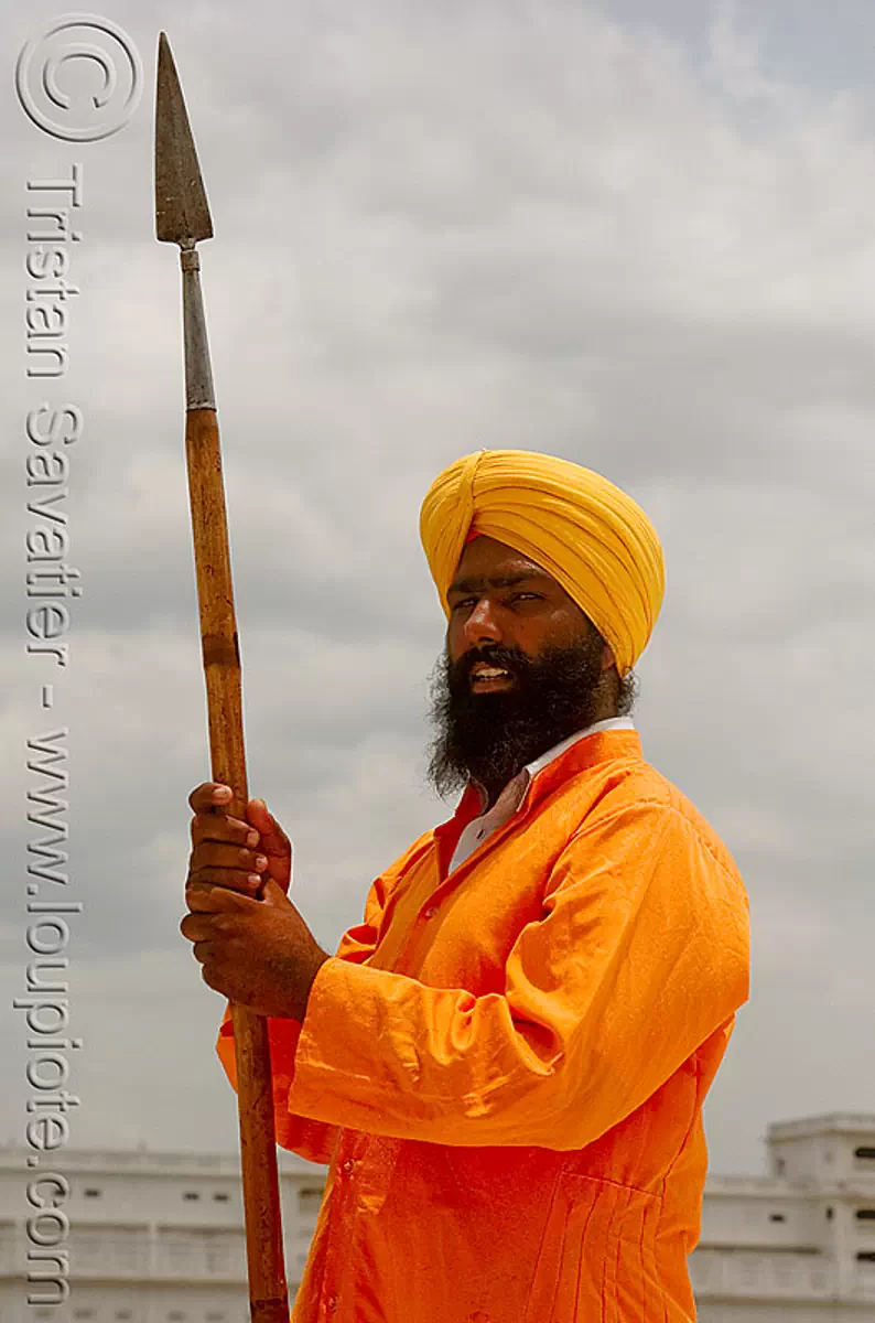 sikh guard with spear at the golden temple, amritsar, india